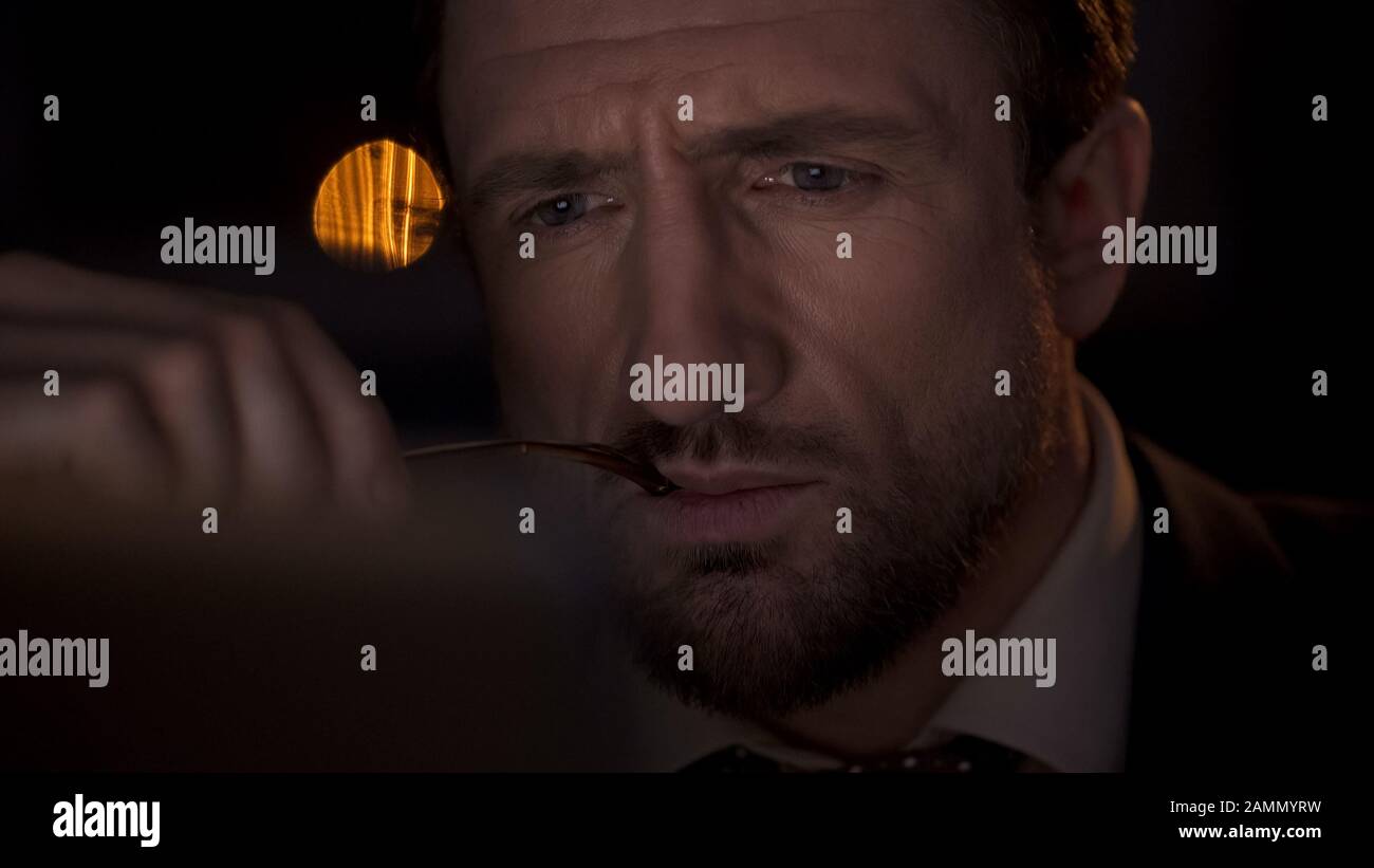 Professional detective working on laptop at night, holding eyeglasses ...