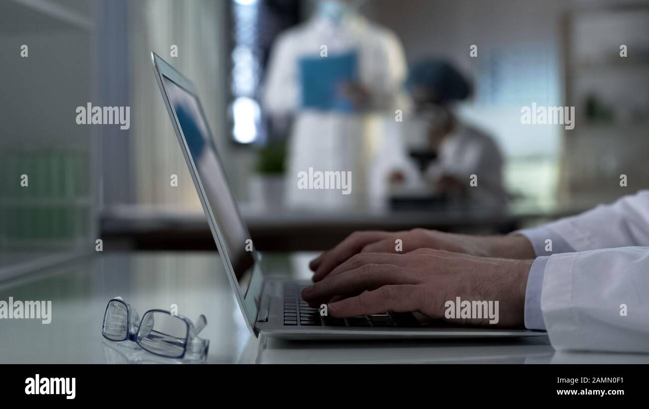 Scientist typing experiment results on laptop, working at project in ...