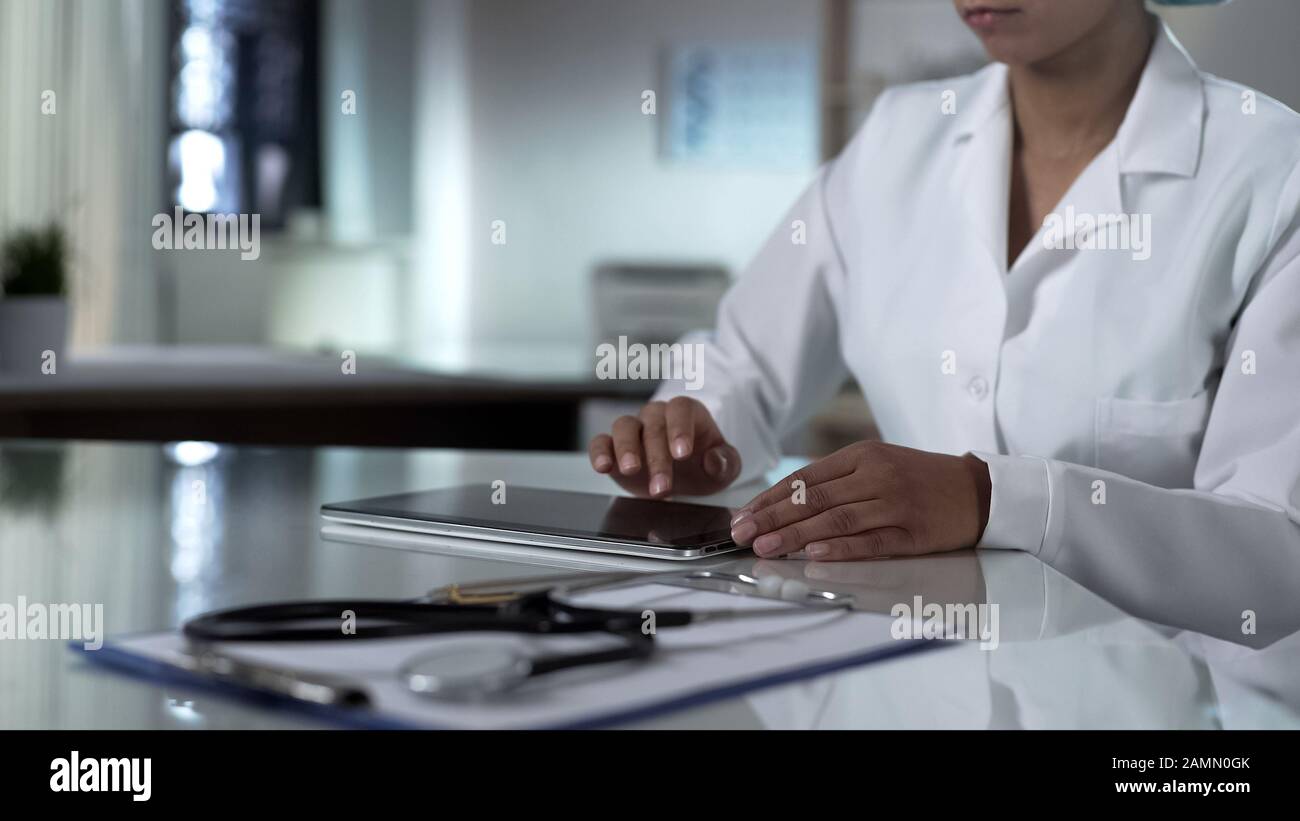 Female doctor scrolling tablet screen, checking patients test results ...