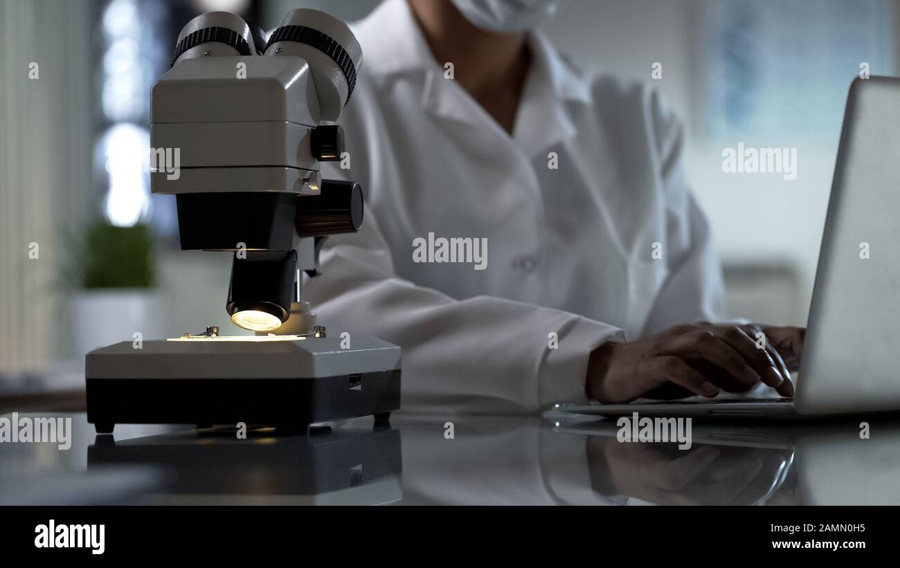 Lab worker writing observations on laptop, experiment results, clinic ...