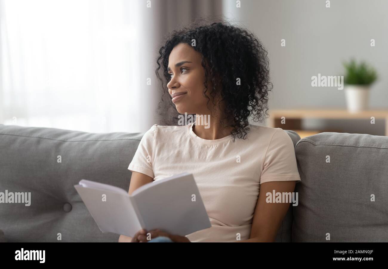 African woman distracted from reading looks out the window Stock Photo ...