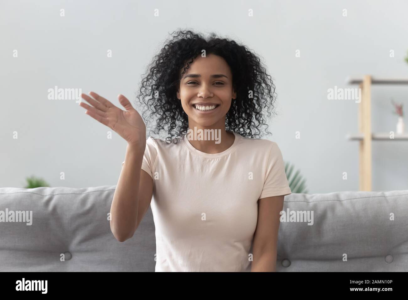African woman feels happy wave hand looking at camera Stock Photo - Alamy