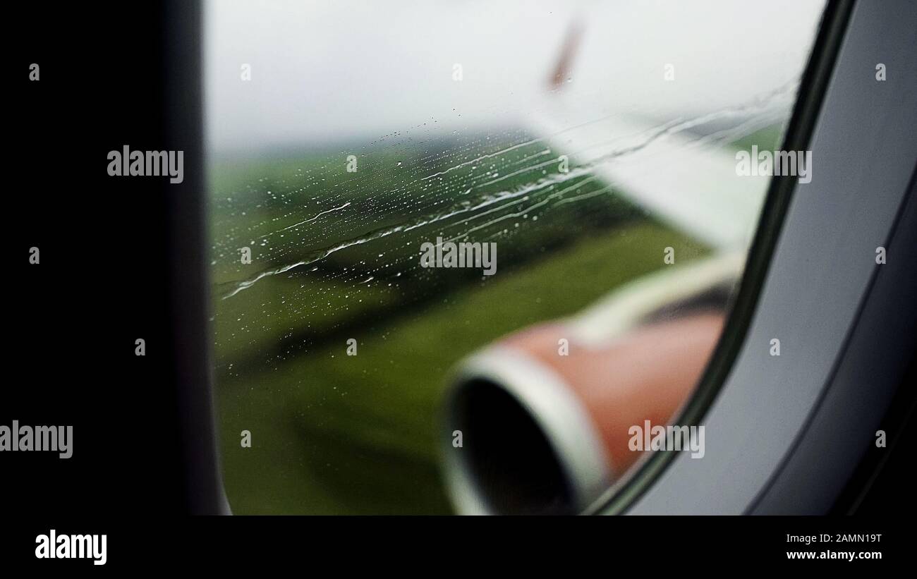 View through rainy window of airplane successfully landing runway at ...