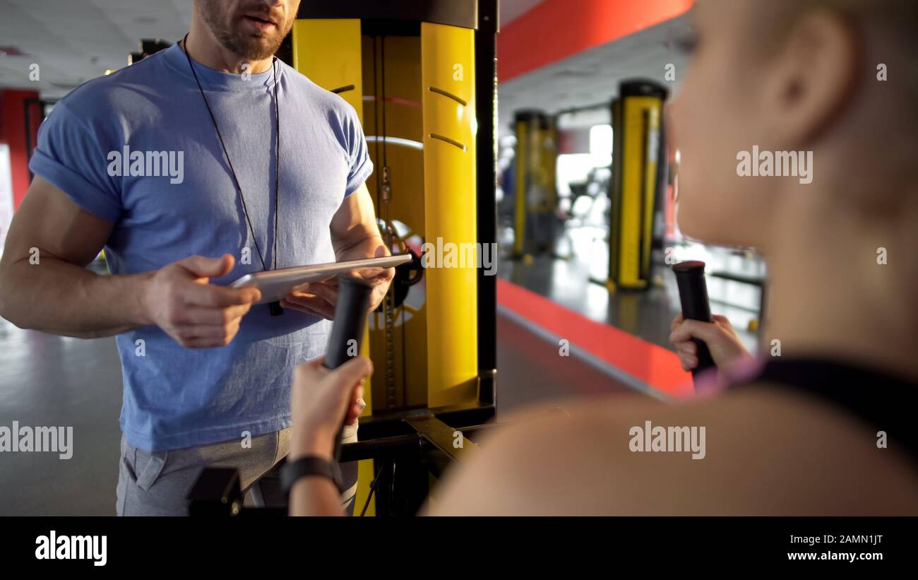 Fitness trainer talking to young woman gym, discussing training program ...