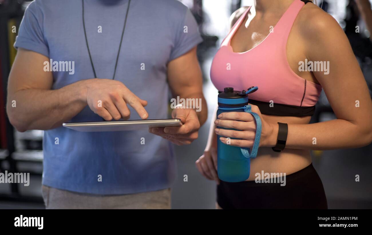 Coach explaining training schedule to female client, using tablet in ...