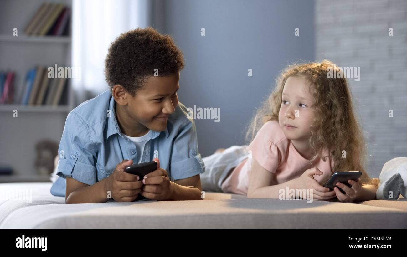Boy and girl looking each other interest while competing mobile game ...
