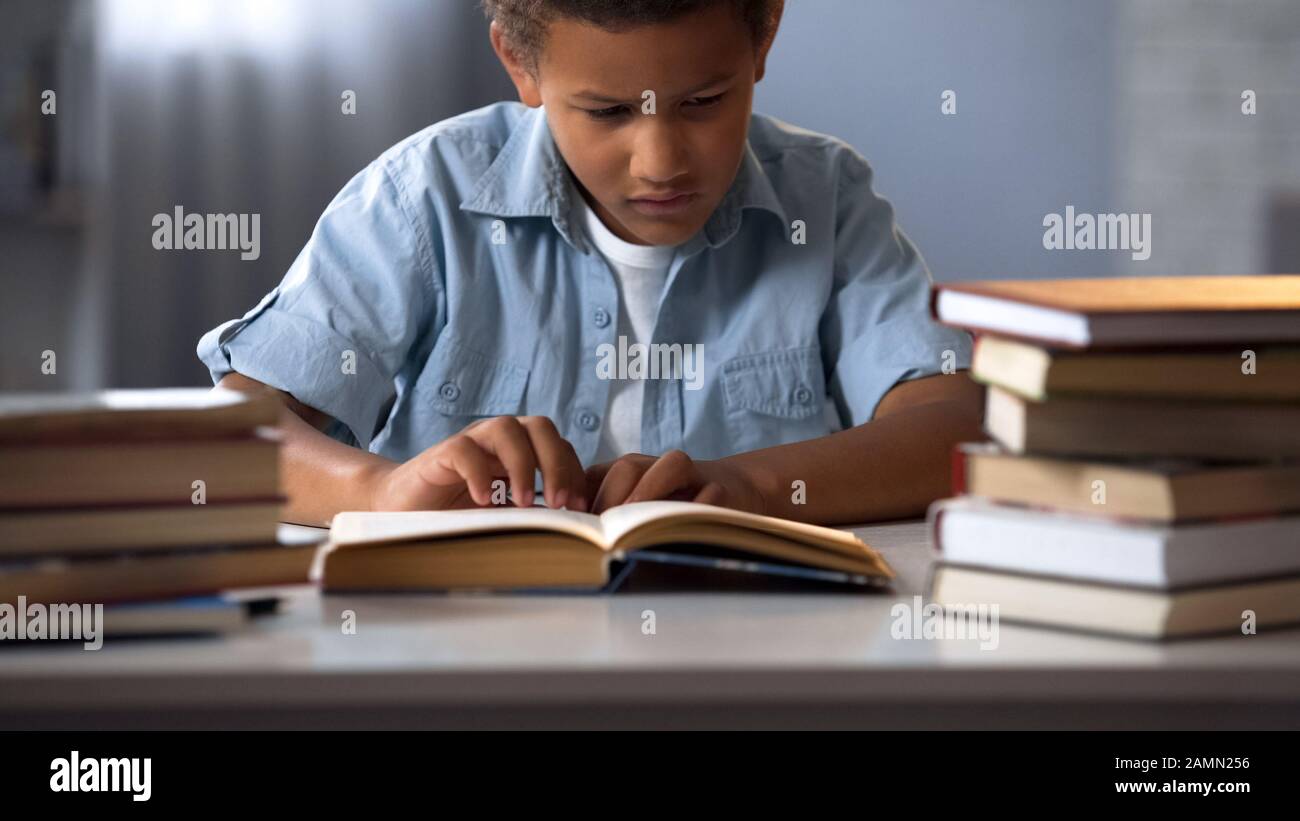 Concentrated school boy doing homework sitting at desk, intensive ...