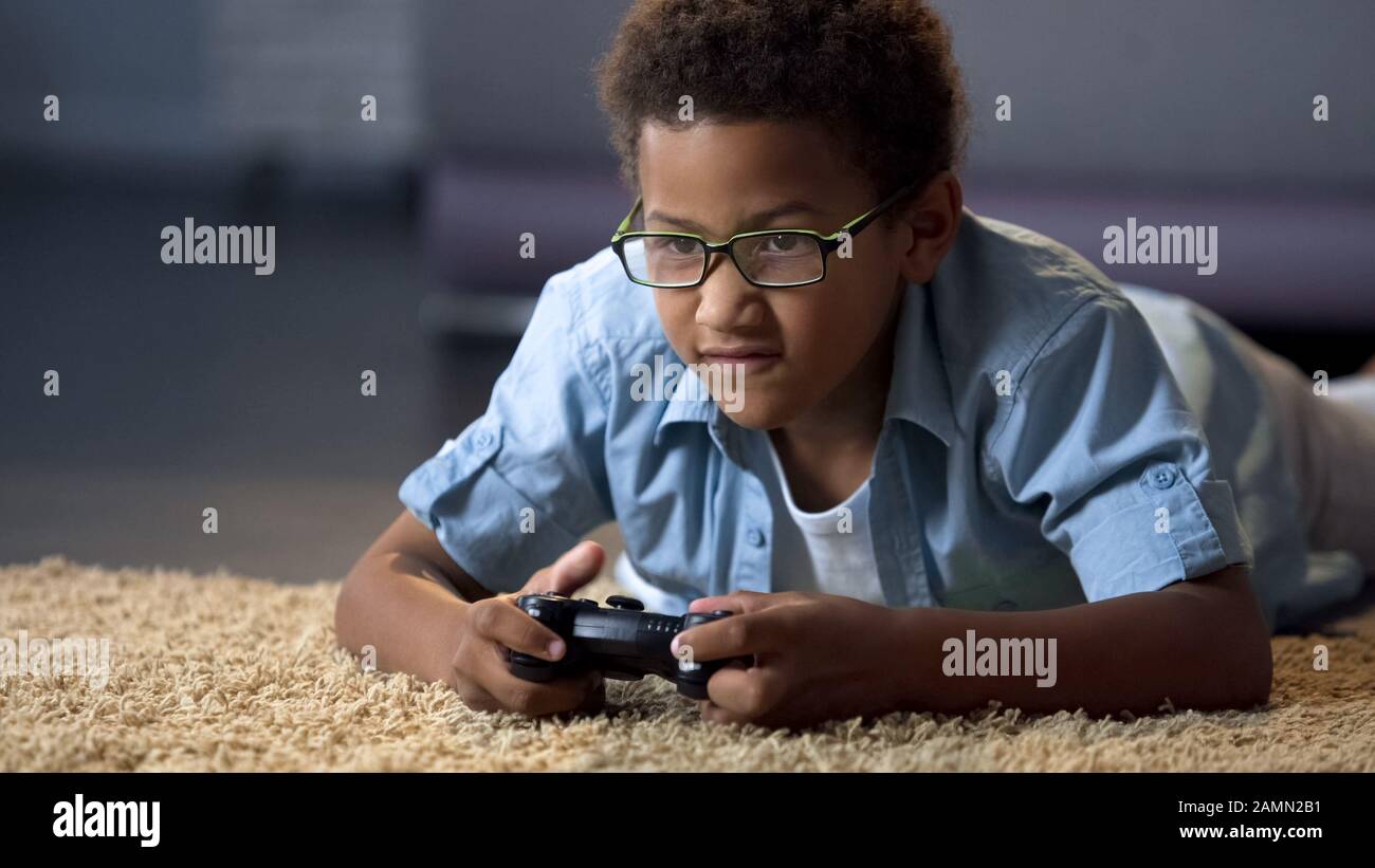 Afro-American boy absorbedly playing on new video game console, home ...