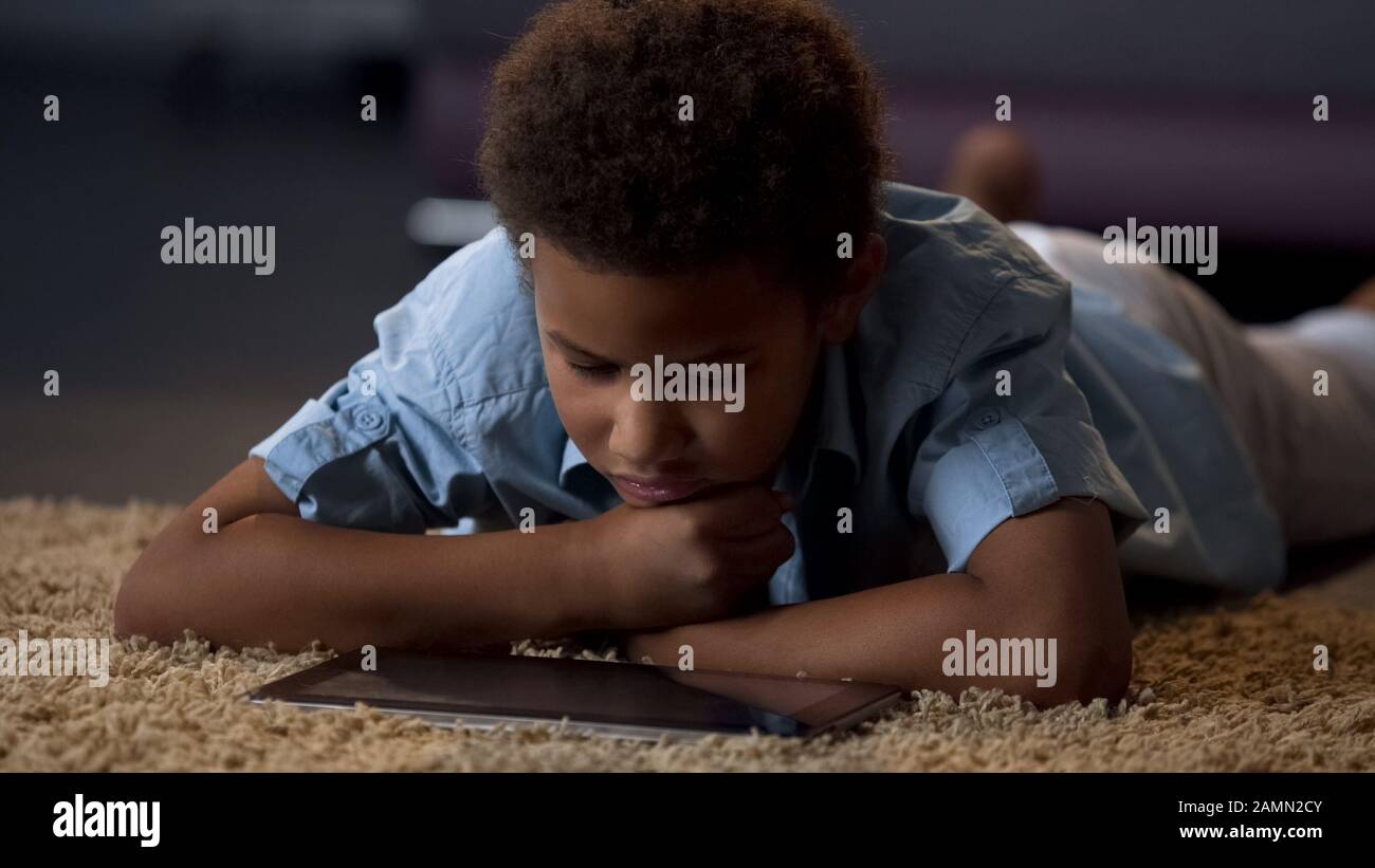 Child watching video on tablet, bored at home, poorly organized leisure ...