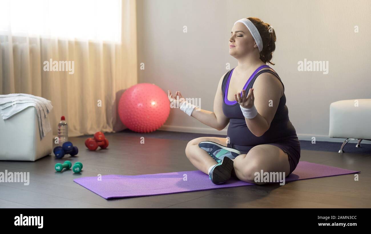Plump girl sitting in lotus position, practicing yoga asana meditation ...