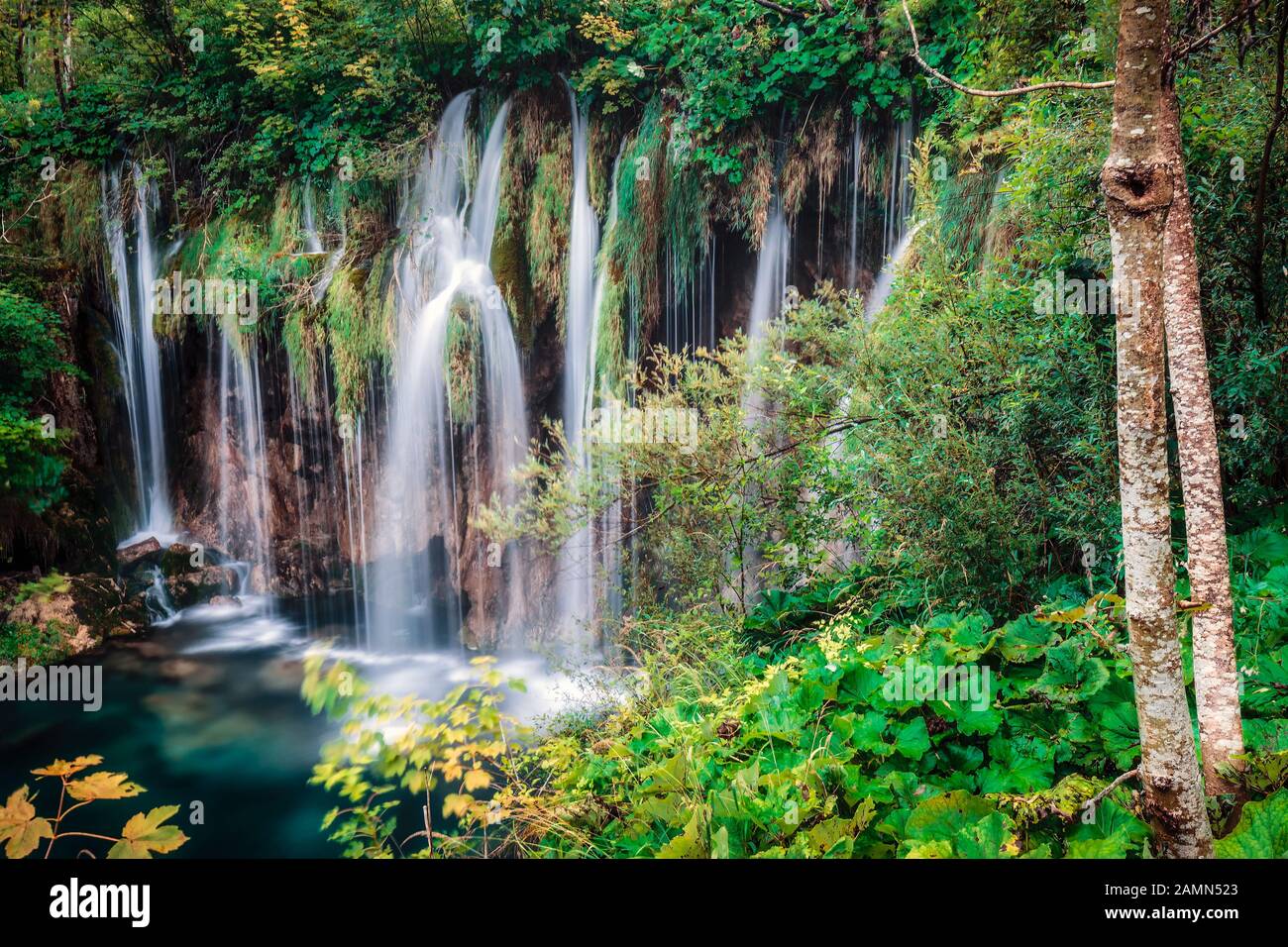 Big waterfall with two aspen trees over emerald lake Stock Photo - Alamy