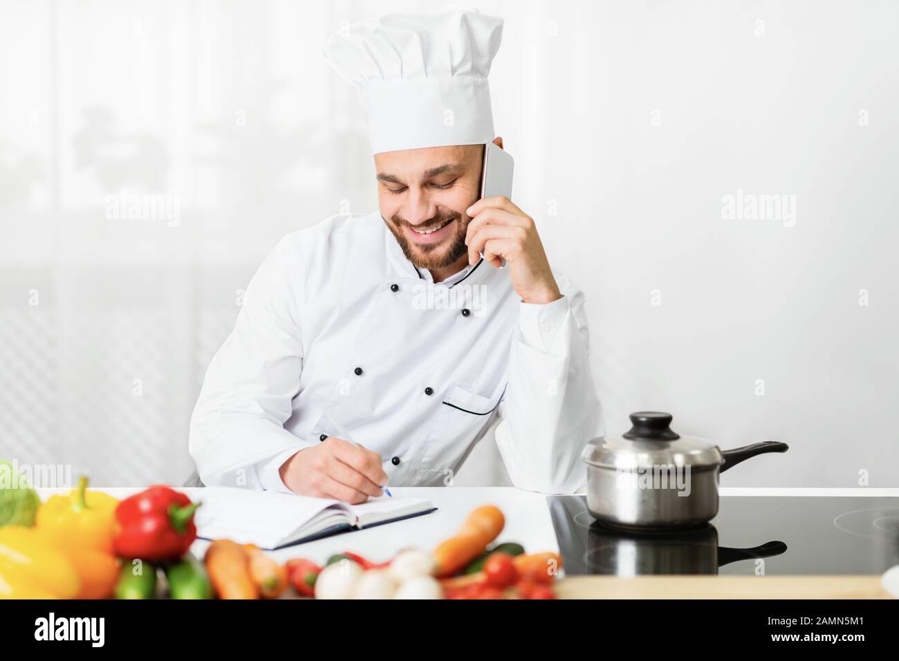 Chef Man Talking On Phone Taking Notes Standing In Kitchen Stock Photo ...