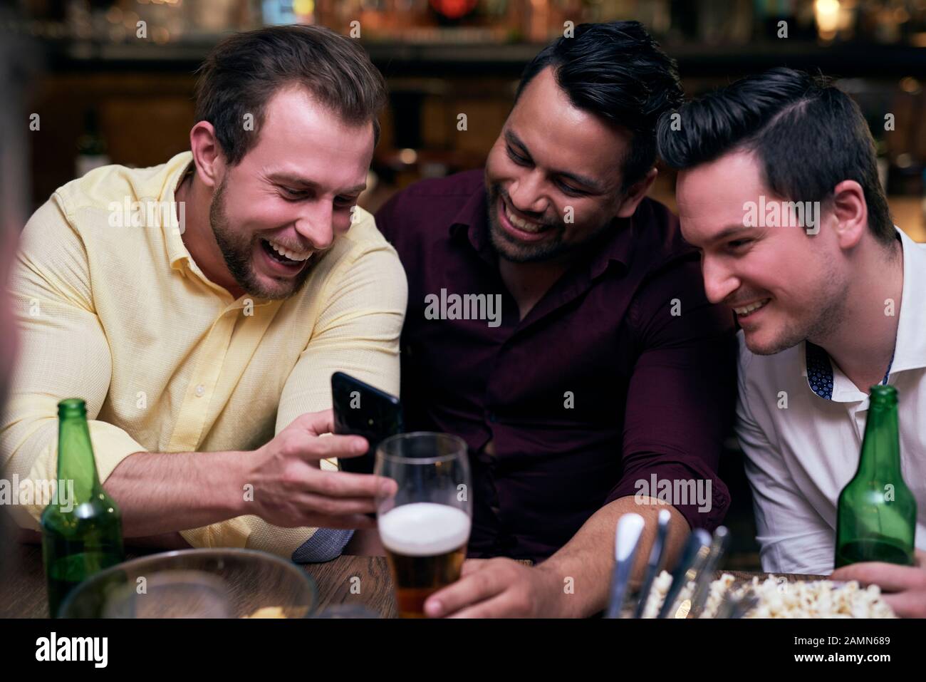 Three men using mobile phone during meeting in the pub Stock Photo - Alamy