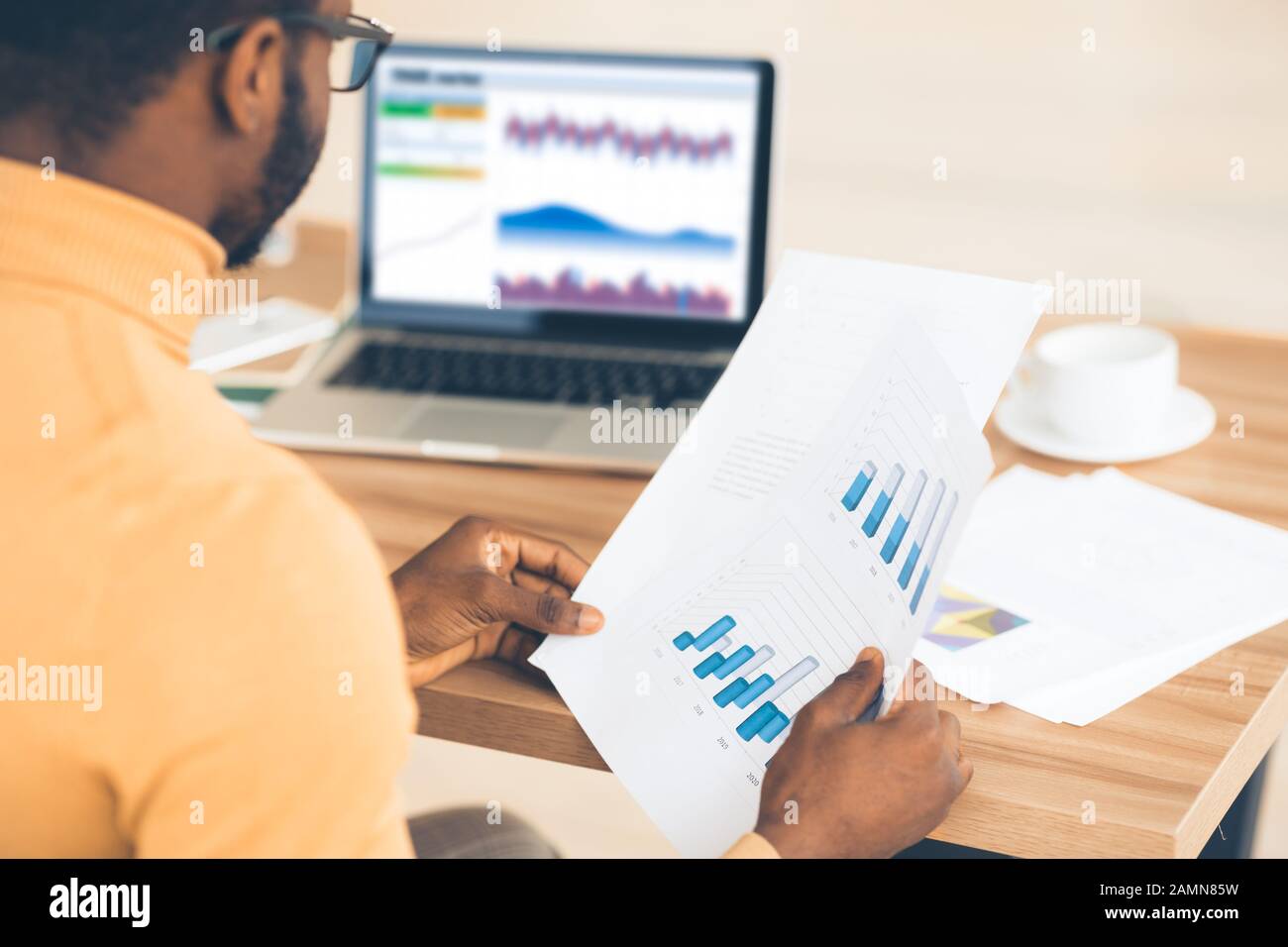 Black manager working with diagrams on pc and paper Stock Photo - Alamy