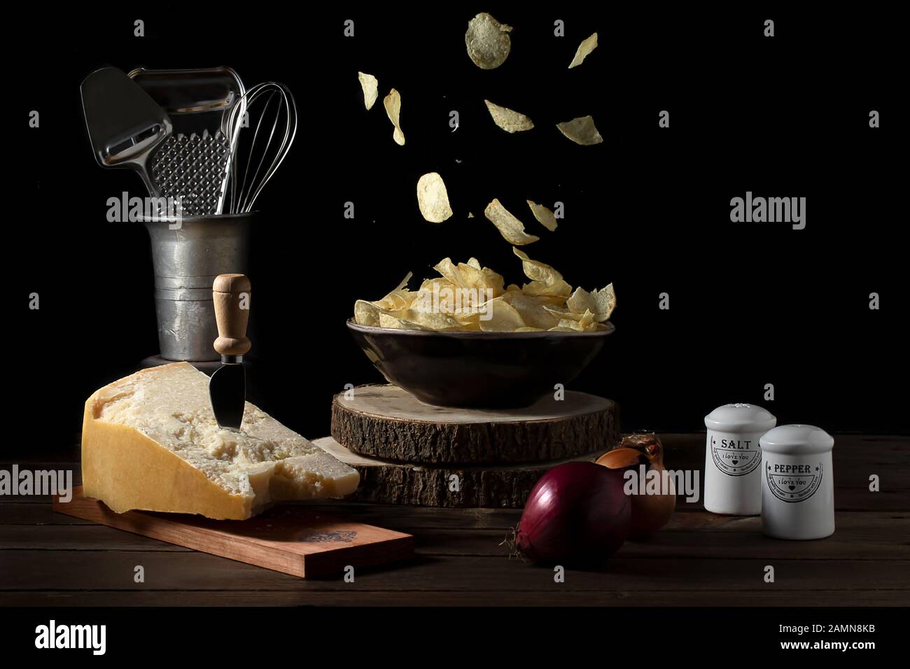 Potato chips falling in a bowl on a table with parmesan cheese, onions ...