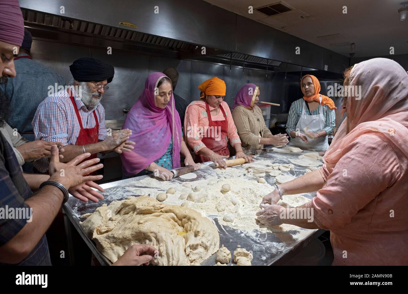 Sikh men & women of various ages make roti breads in a langar, free ...
