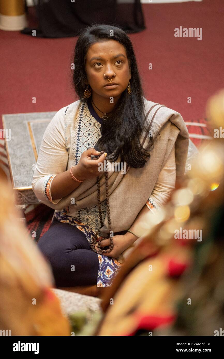 A Hindu priestess in meditative prayer while looking at statues of ...