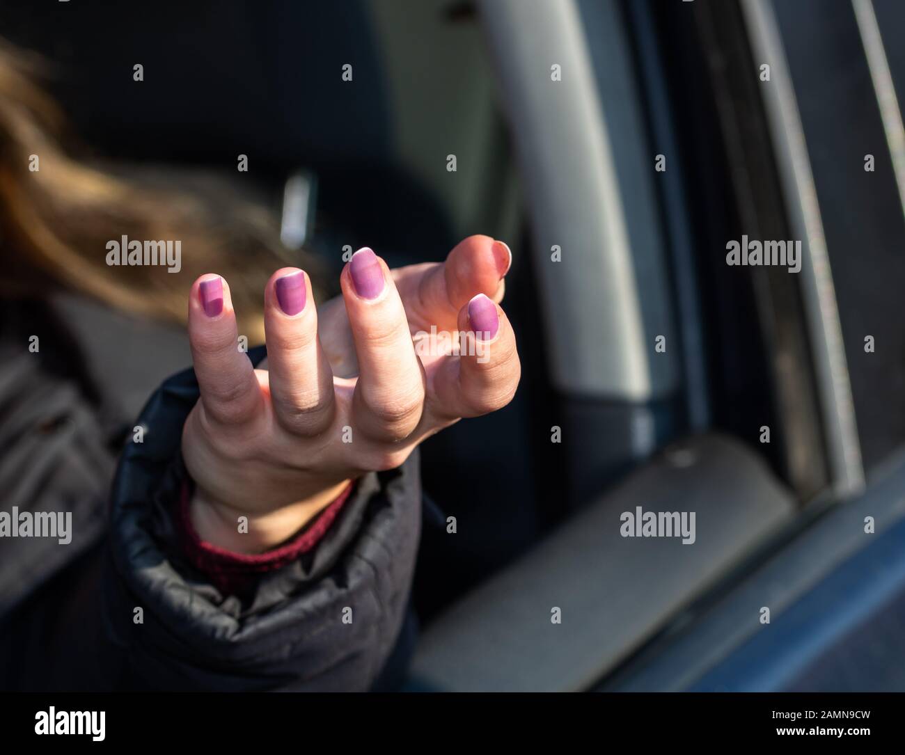 Aggressive woman gesticulates with hand out of window while driving ...