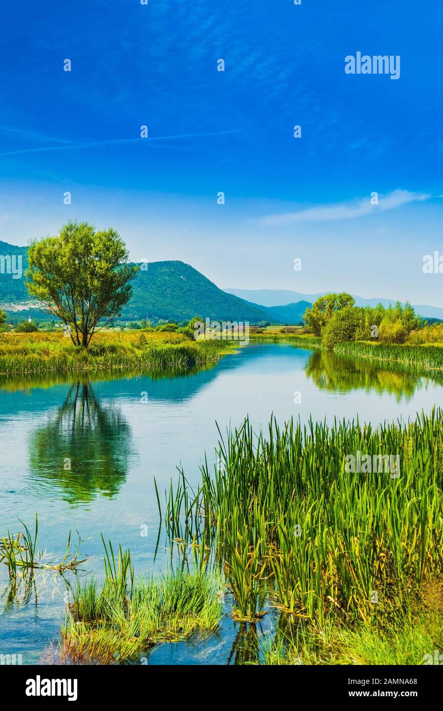 Beautiful Gacka river flowing between green fields, summer view, Lika ...