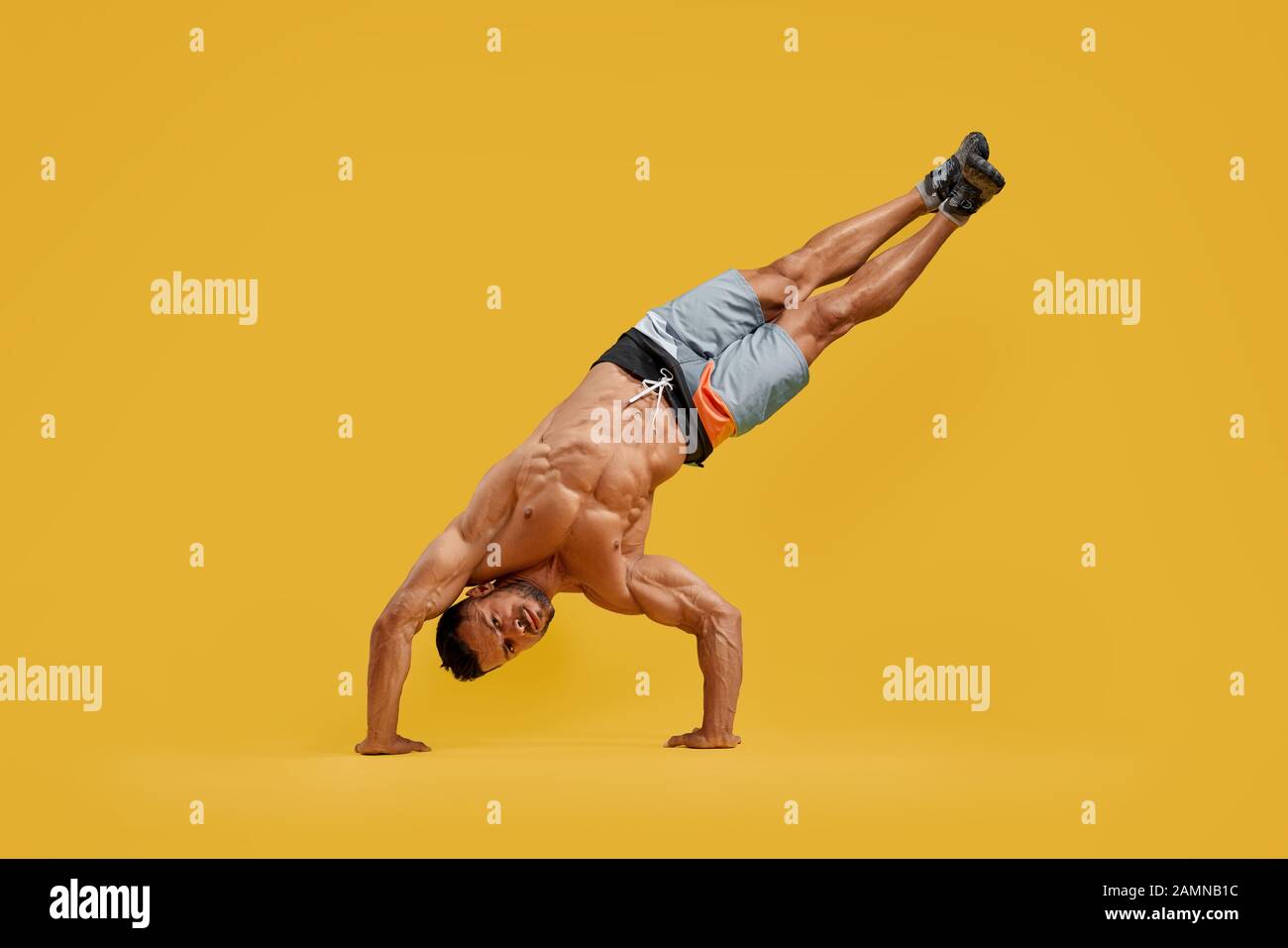 Front view of muscular bodybuilder with perfect abs doing handstand ...