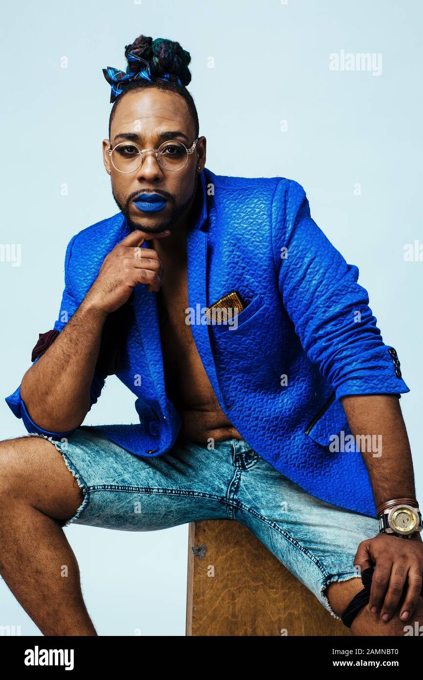 Portrait of a man with blue lips dressing in blue sitting . Studio ...