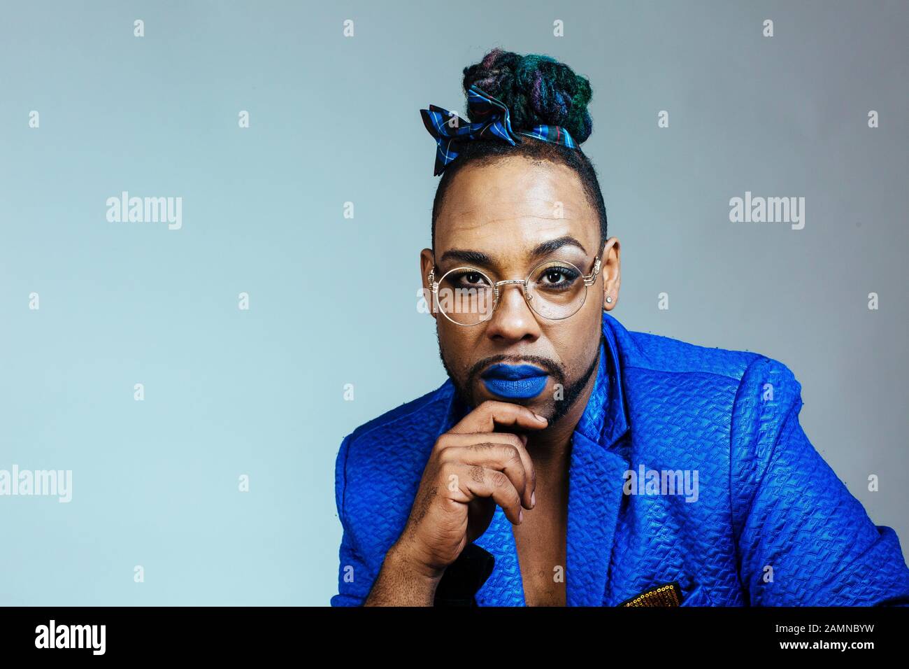 Portrait of a man with blue lips dressing in blue sitting . Studio ...