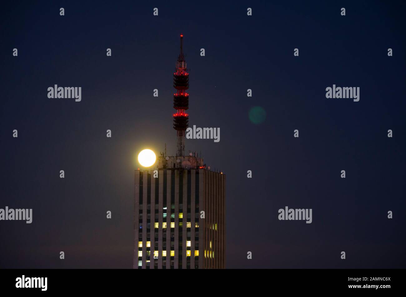 Full moon in the city. Tall building with a spire antenna Stock Photo ...