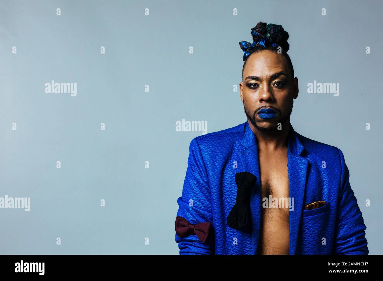 portrait of a man with blue lips dressing in blue sitting . Studio ...