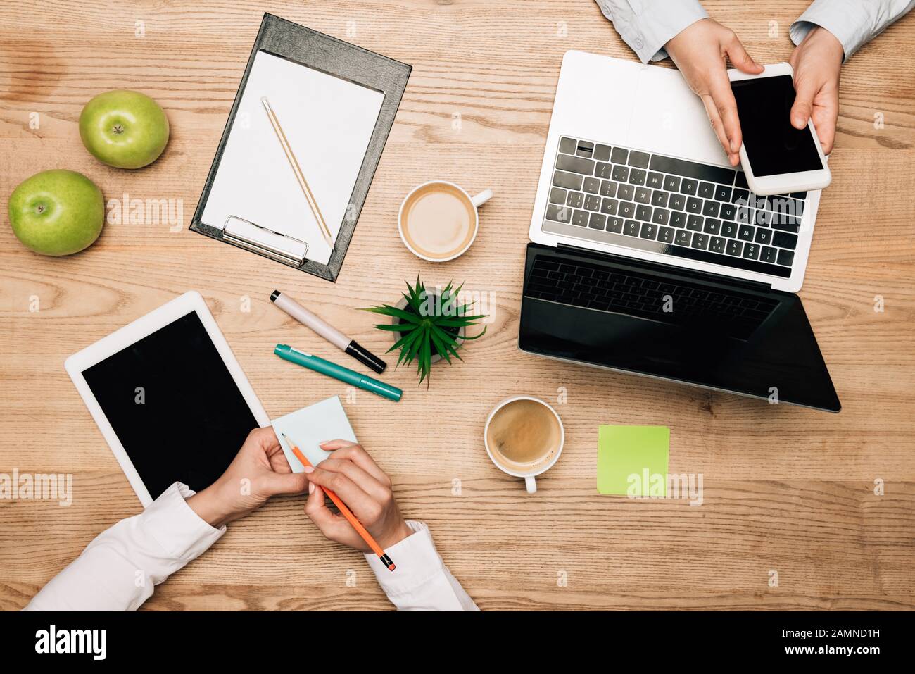 Top view of business partners with digital devices, sticky notes and ...