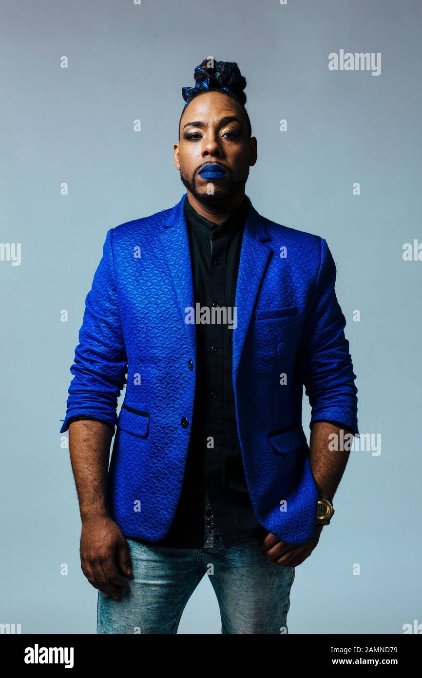 portrait of a man with blue lips dressing in blue sitting . Studio ...
