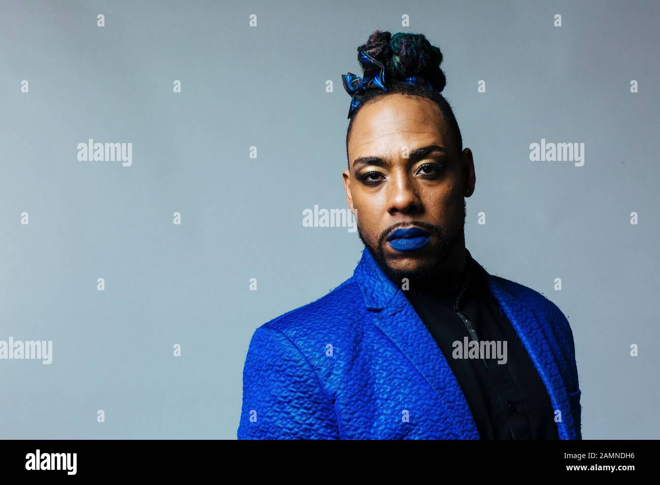 portrait of a man with blue lips dressing in blue sitting . Studio ...