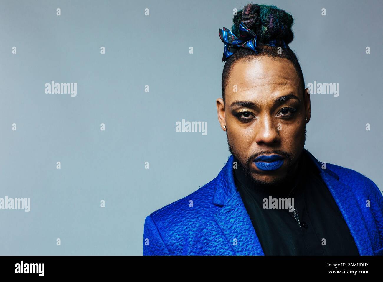 portrait of a man with blue lips dressing in blue sitting . Studio ...