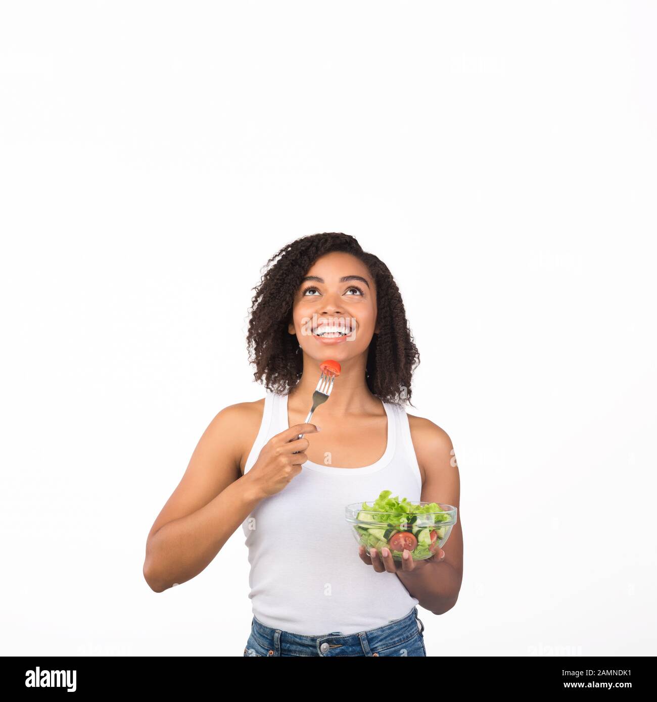 Excited black girl eating salad from bowl Stock Photo - Alamy