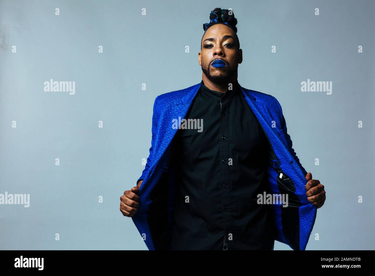 portrait of a man with blue lips dressing in blue sitting . Studio ...