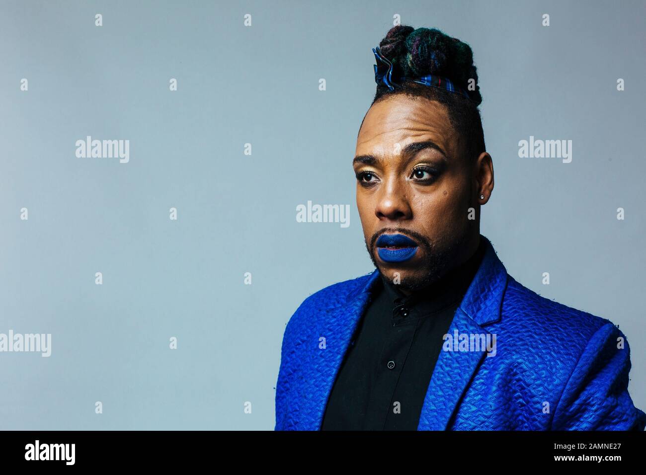 portrait of a man with blue lips dressing in blue sitting . Studio ...