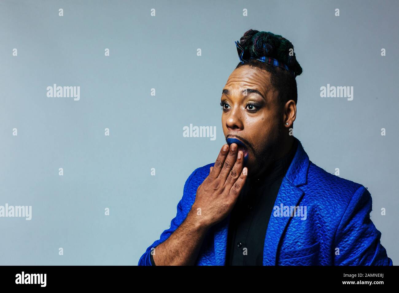 portrait of a man with blue lips dressing in blue sitting . Studio ...