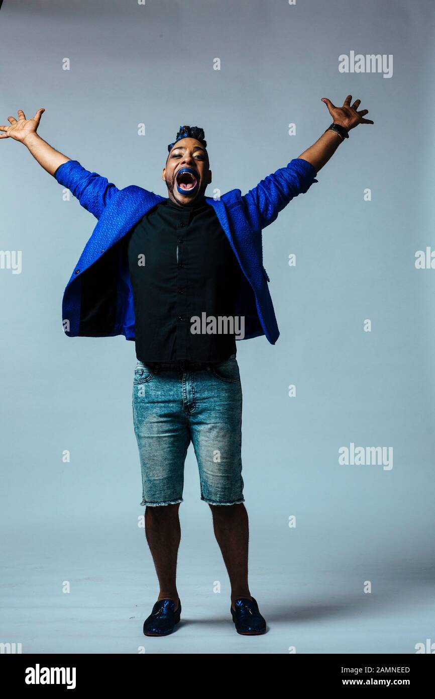portrait of a man with blue lips dressing in blue sitting . Studio ...