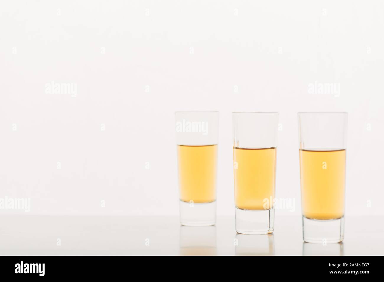 three shots with alcohol in row isolated on white Stock Photo - Alamy