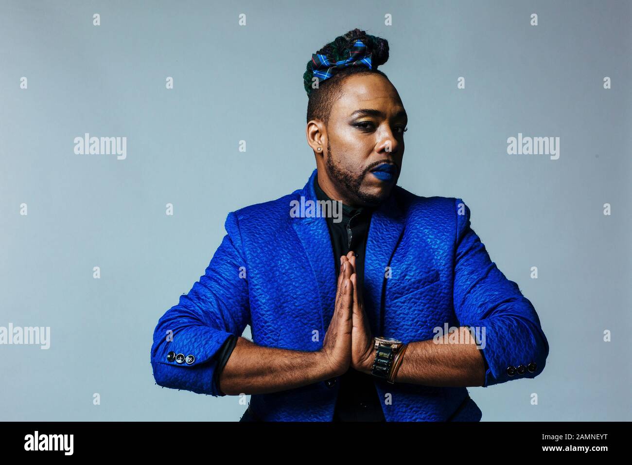 portrait of a man with blue lips dressing in blue sitting . Studio ...