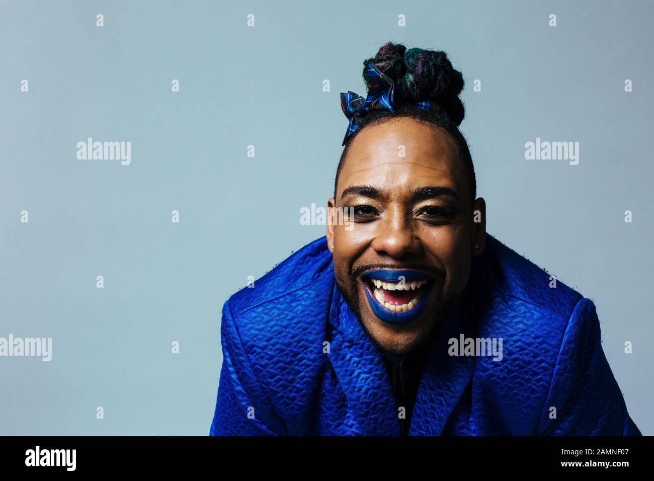 portrait of a man with blue lips dressing in blue sitting . Studio ...