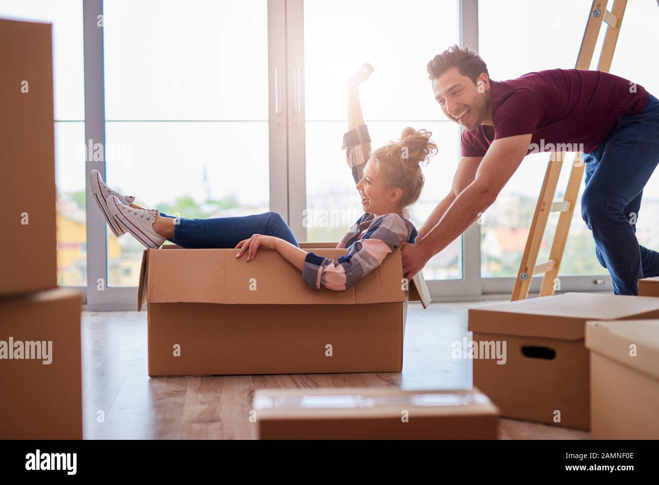 Playful couple having fun with boxes during move house Stock Photo - Alamy