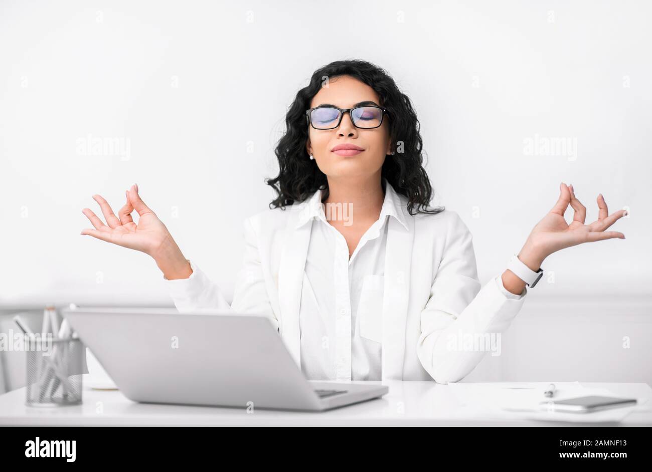 Calm hispanic manager meditating at work place Stock Photo - Alamy