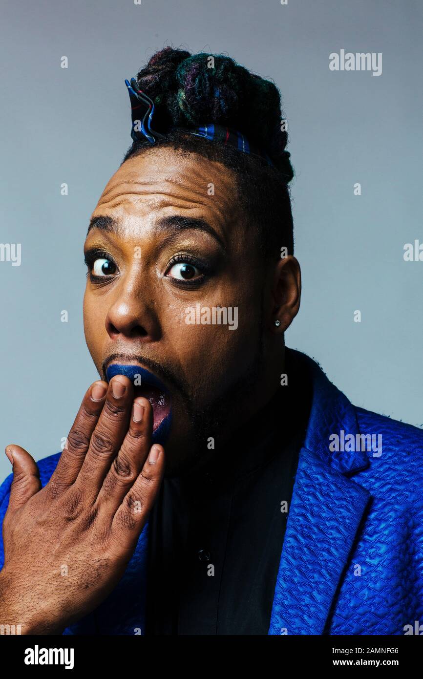 portrait of a surprised man with blue lips dressing in blue sitting ...