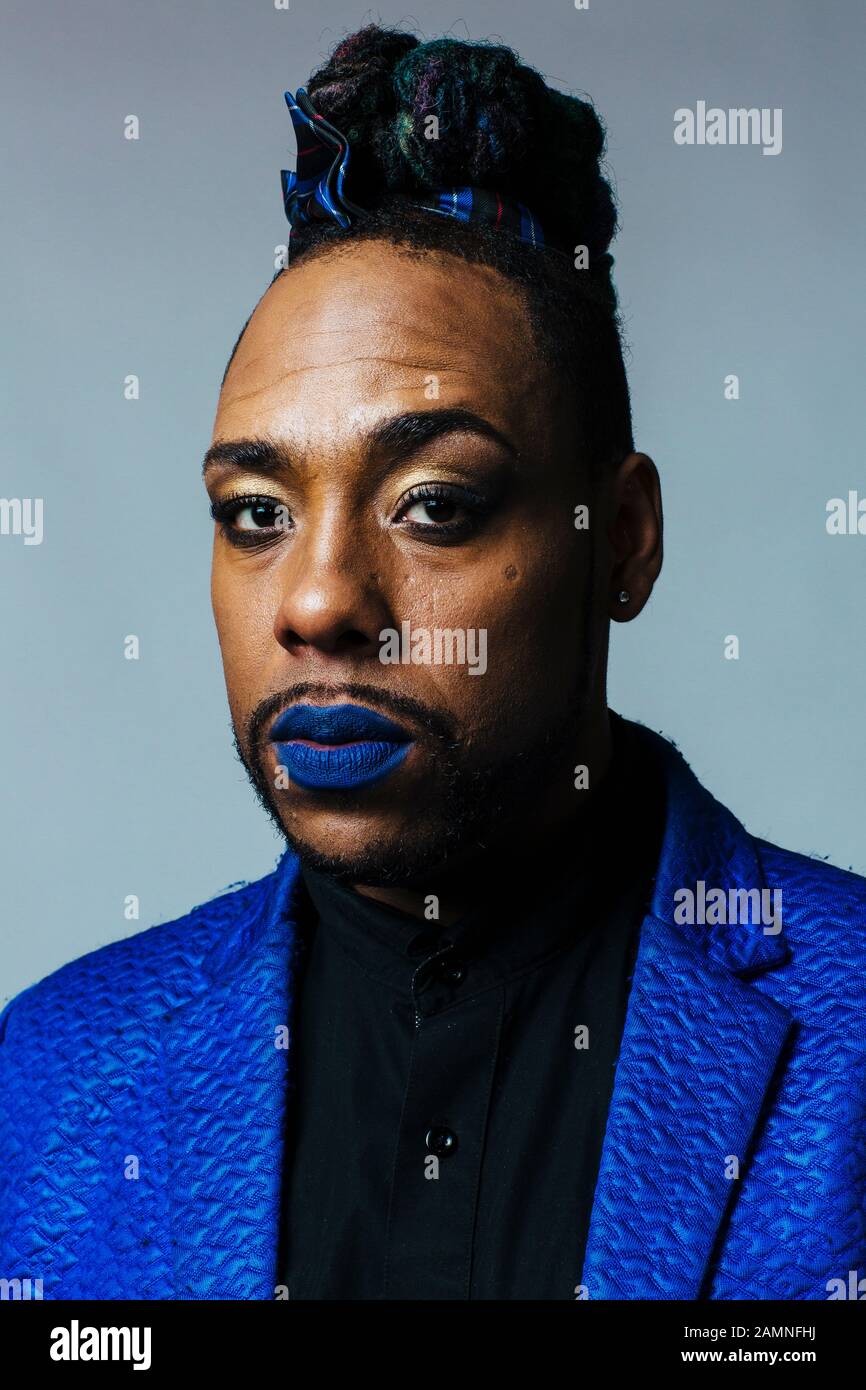 portrait of a man with blue lips dressing in blue sitting . Studio ...