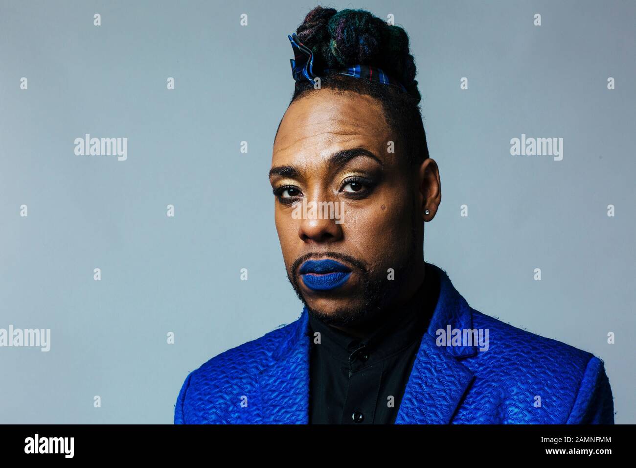 portrait of a man with blue lips dressing in blue sitting . Studio ...