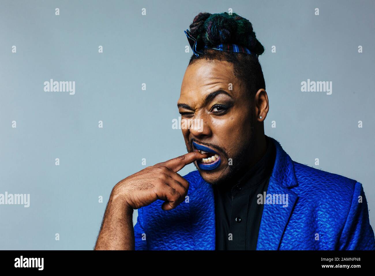 portrait of a man with blue lips dressing in blue sitting . Studio ...