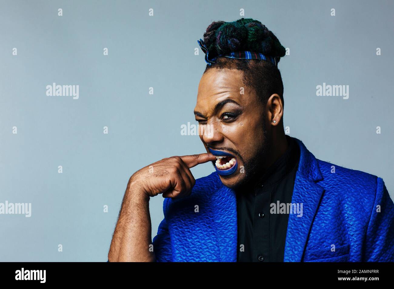 portrait of a man with blue lips dressing in blue sitting . Studio ...