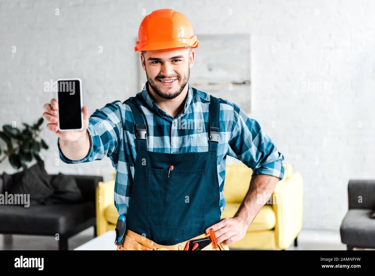 happy worker holding smartphone with blank screen and standing with ...