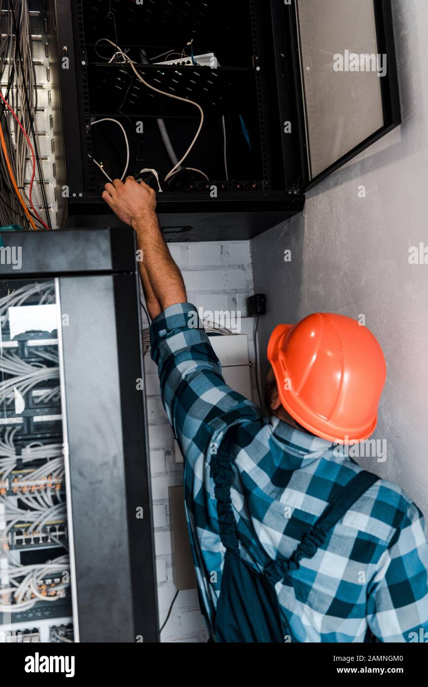 back view of man in safety helmet touching wires and cables Stock Photo ...
