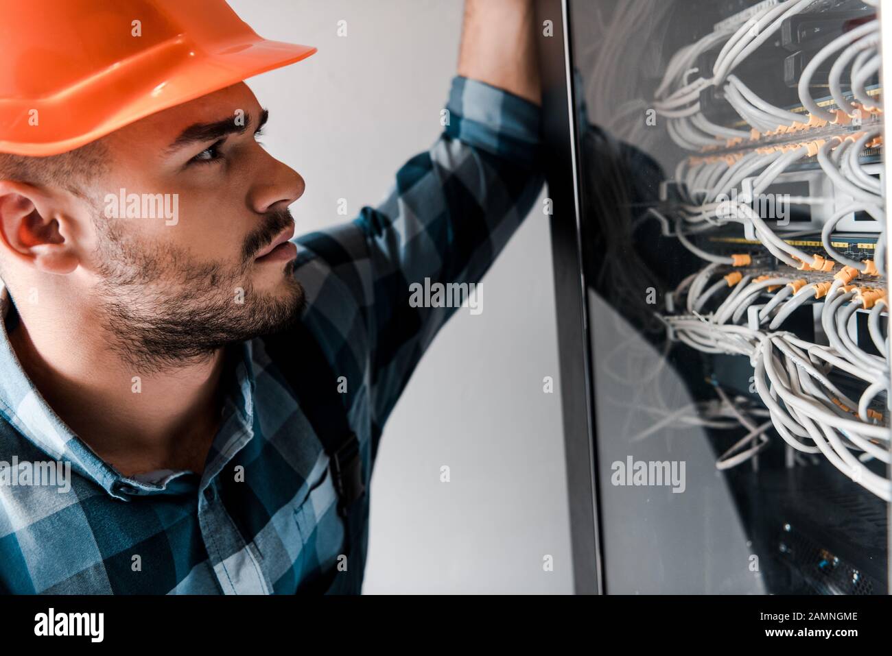 handsome technician in safety helmet looking at wires and cables Stock ...
